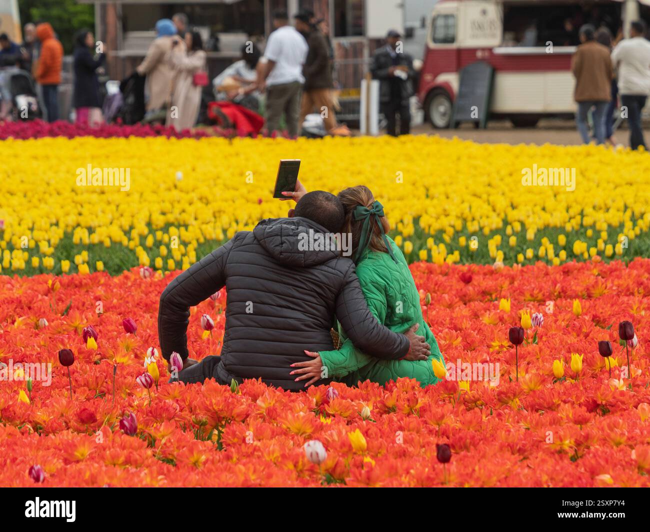 Rear view of an unidentifiable couple taking selfies among colourful ...