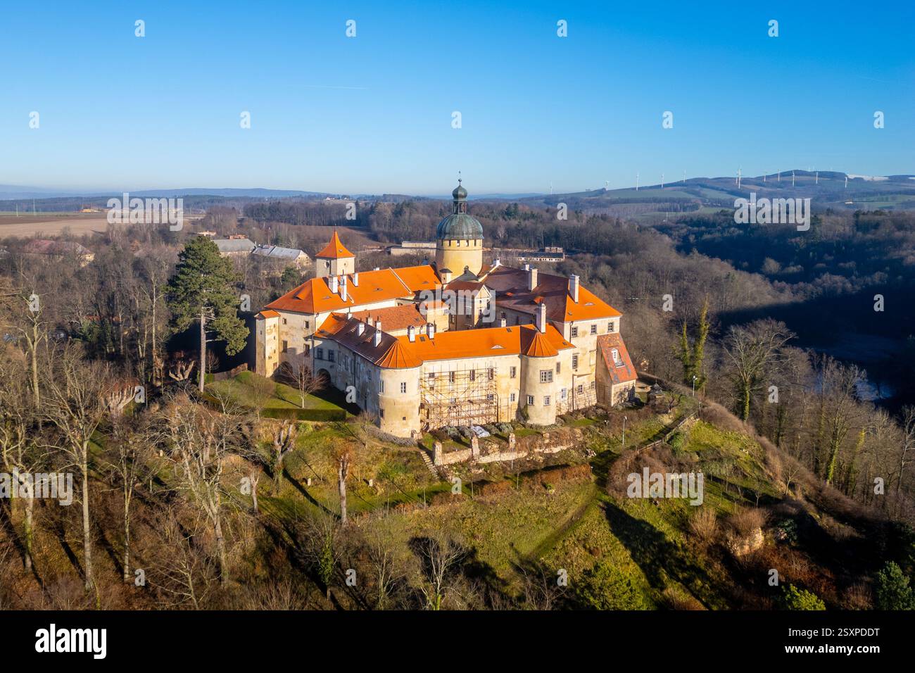 Grabstejn castle stands majestically on a hill, surrounded by lush greenery. The clear blue sky ...
