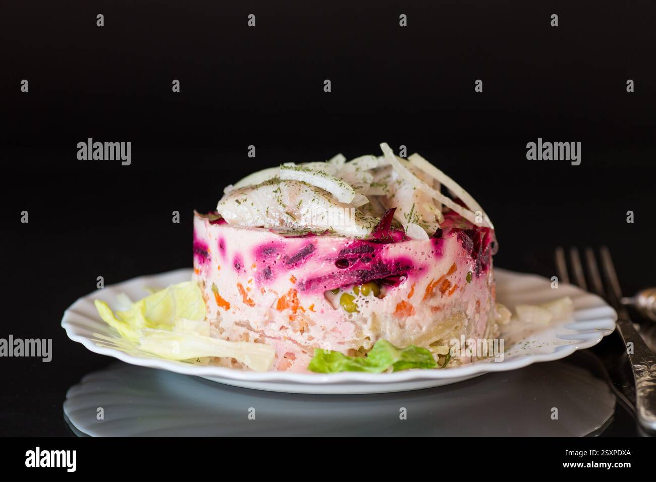 layered vegetable salad with beets and herring, isolated on black ...