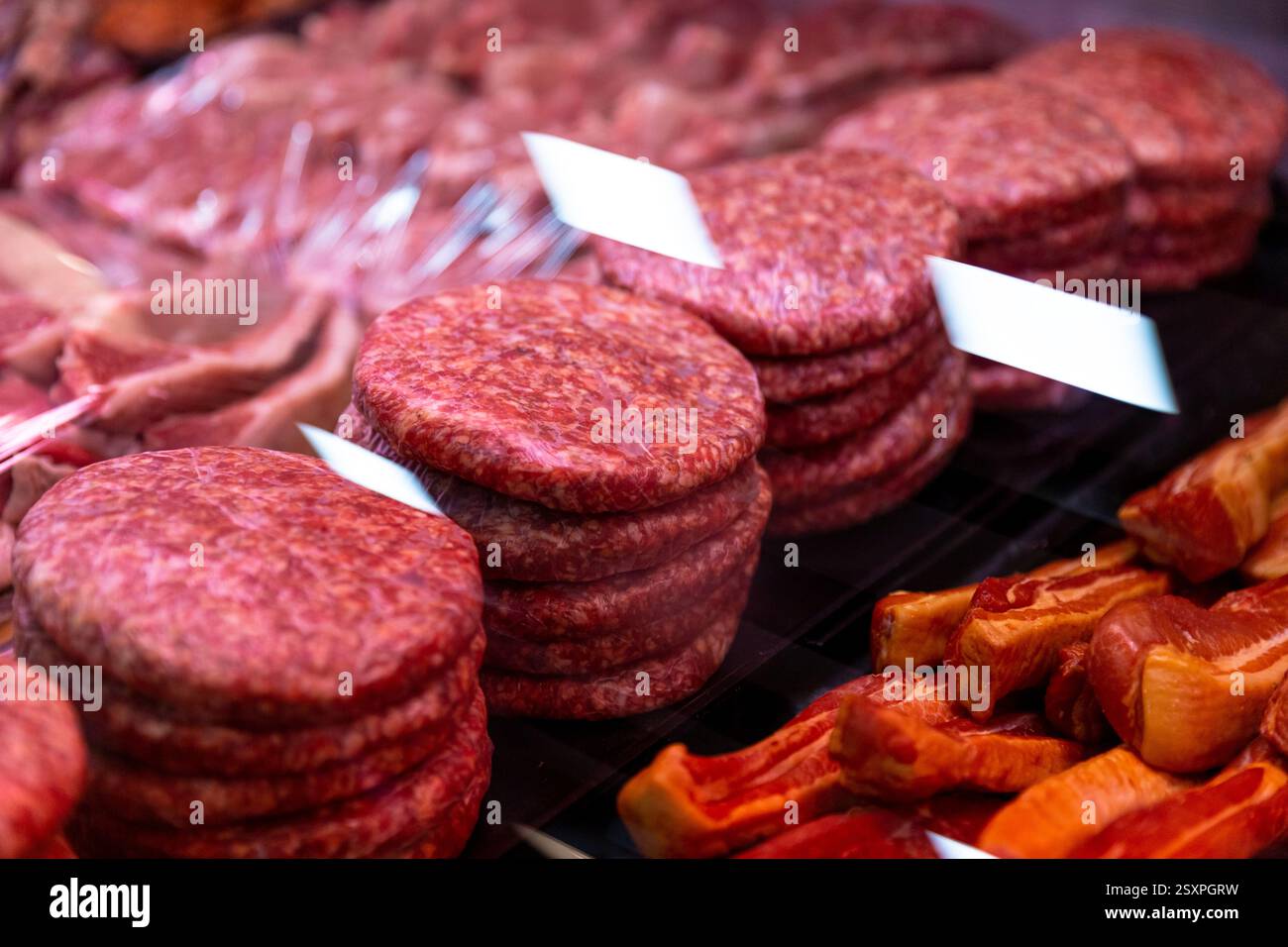 Burger cutlets on display in butchers shop vitrine made of beef meat ...