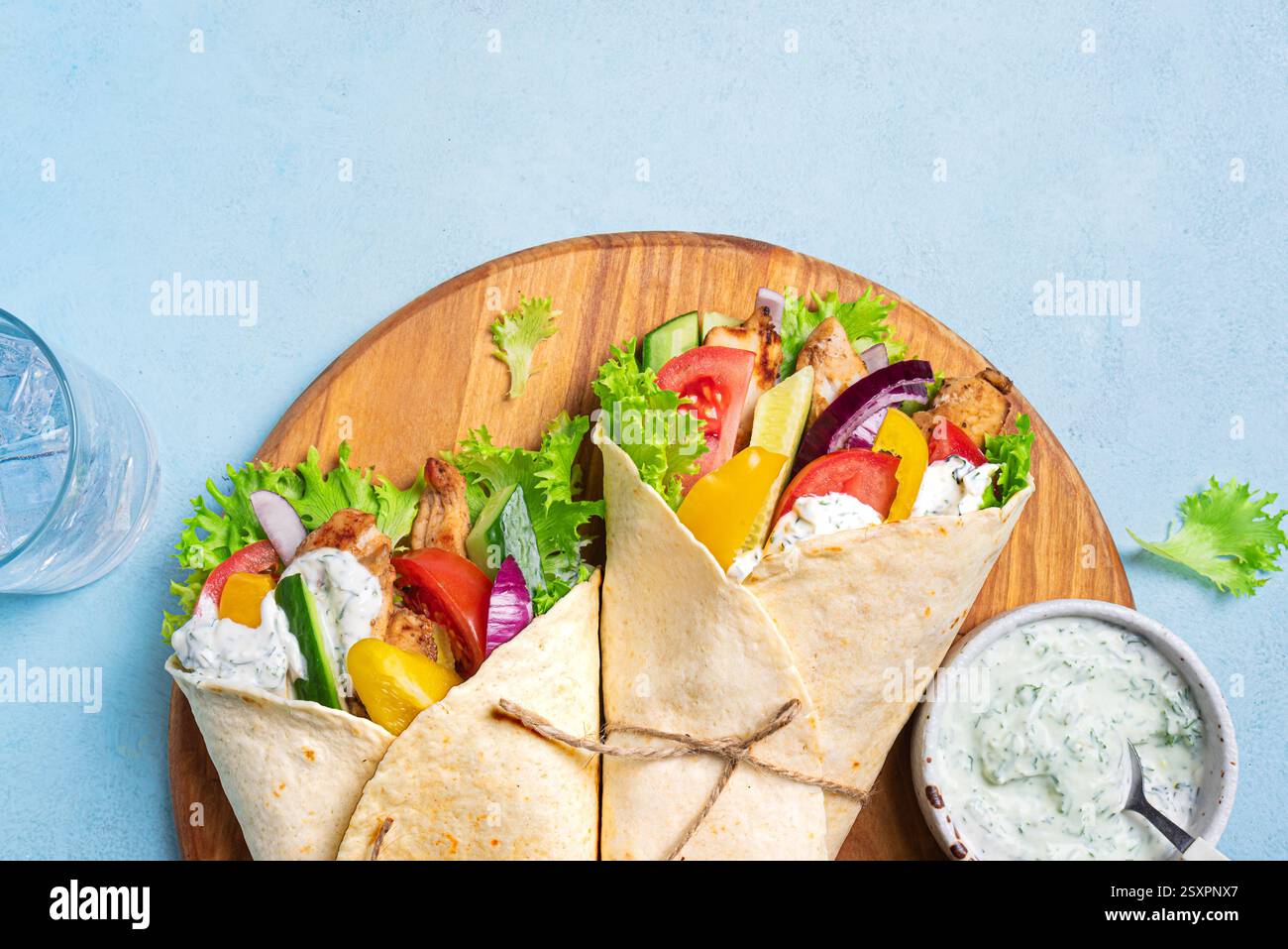 Chicken gyros wrap with vegetables and tzatziki sauce close-up. Healthy ...