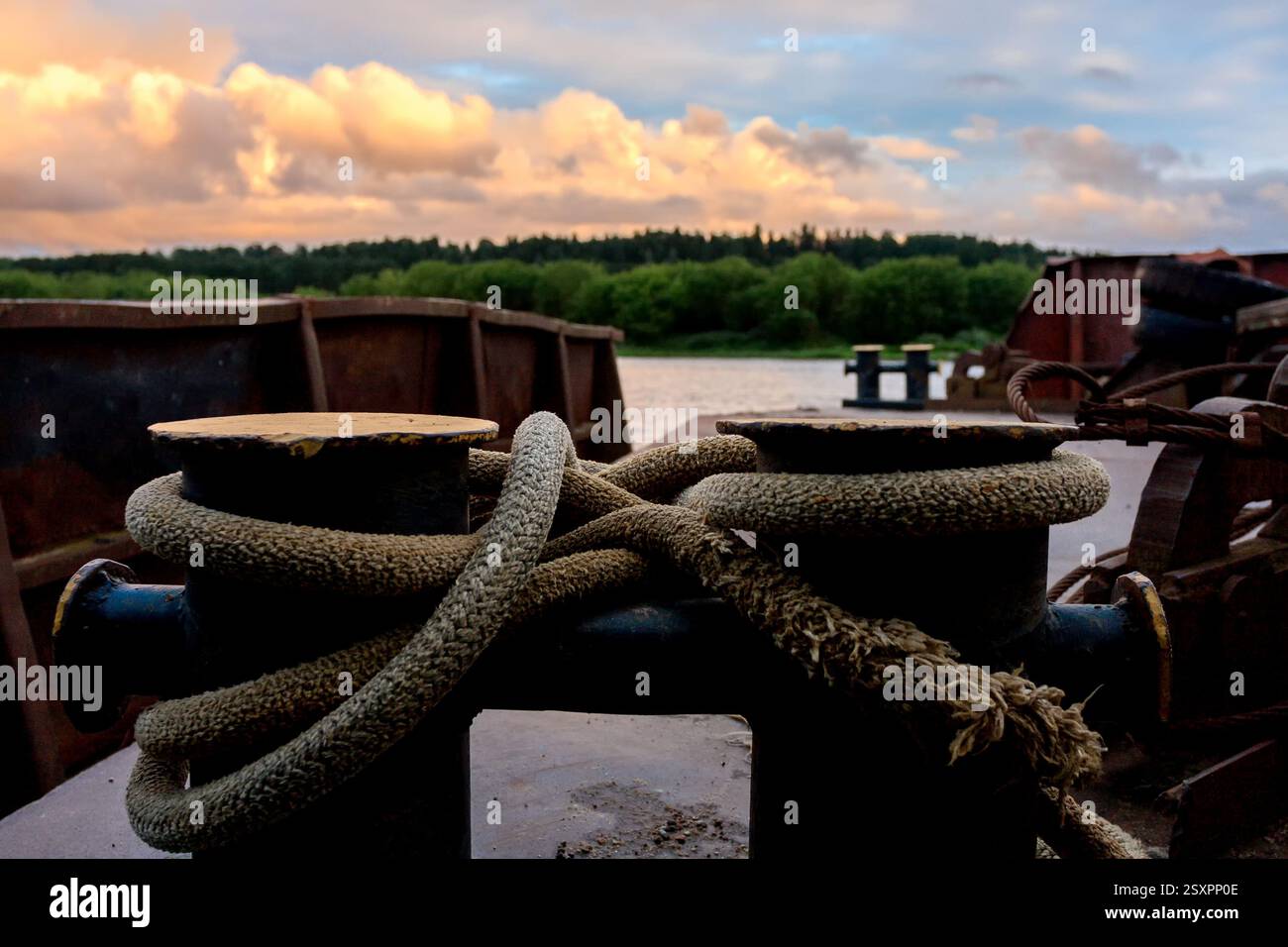 A close-up of a thick mooring rope wrapped around a metal bollard on a ...