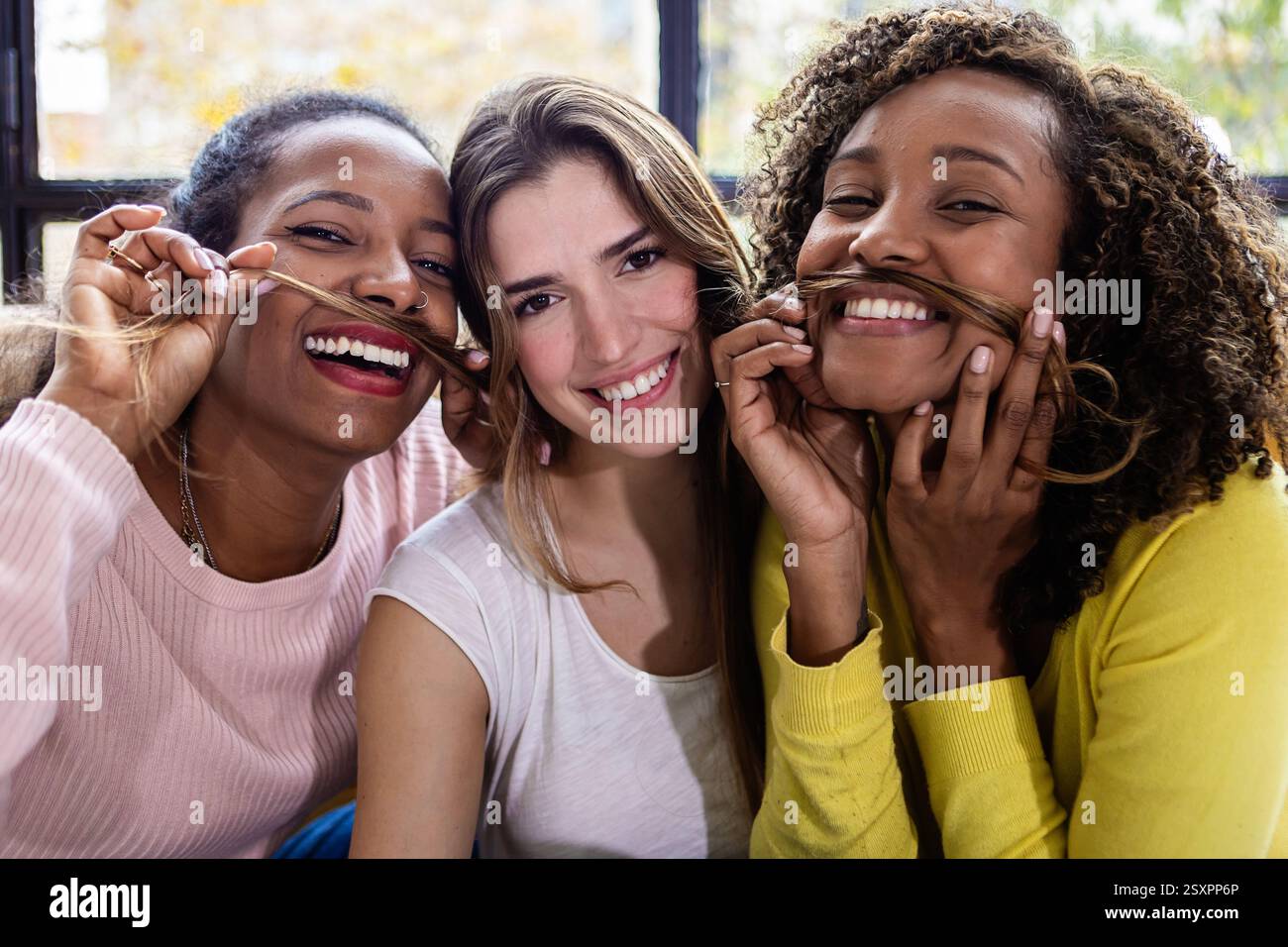 Three playful young women making fake mustaches with hair Stock Photo - Alamy