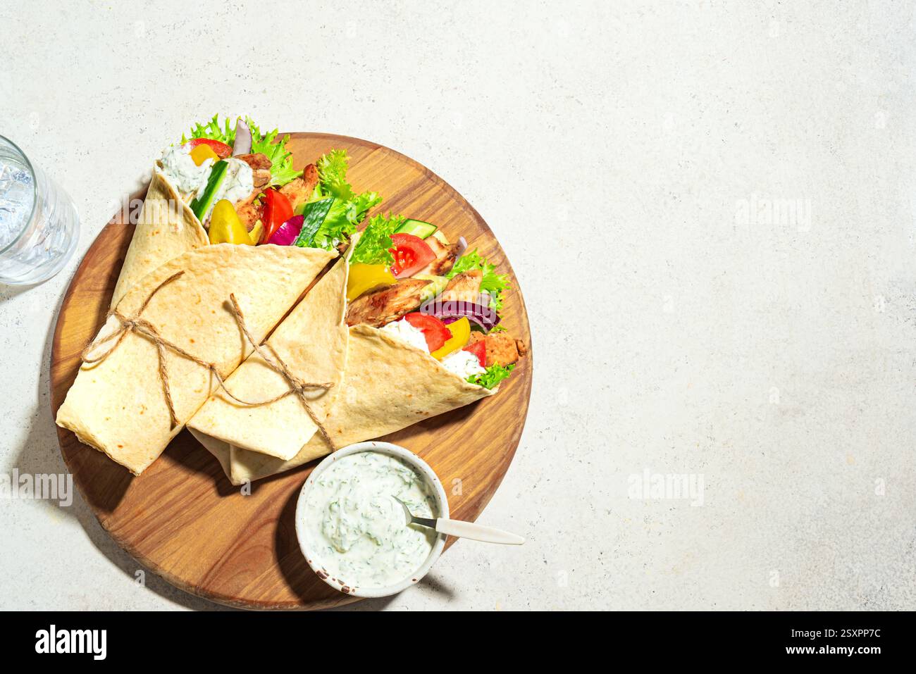 Chicken gyros wrap with vegetables and tzatziki sauce on white ...