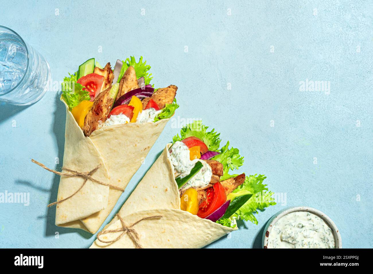 Greek chicken gyros wrap with vegetables and tzatziki sauce on blue ...