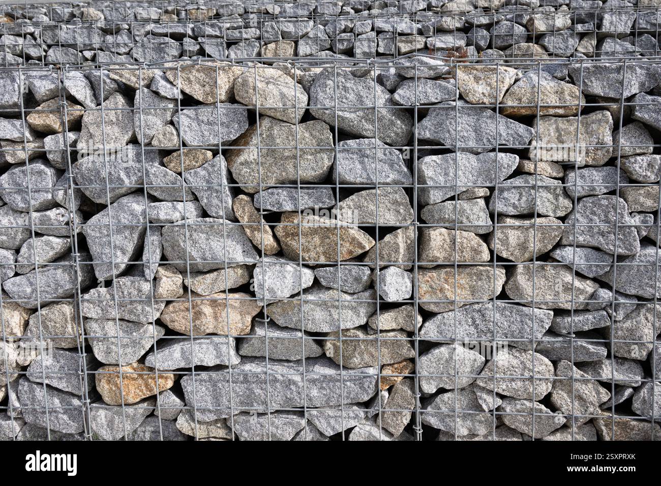 Abstract background of a gabion walls made of granite stones and wire ...