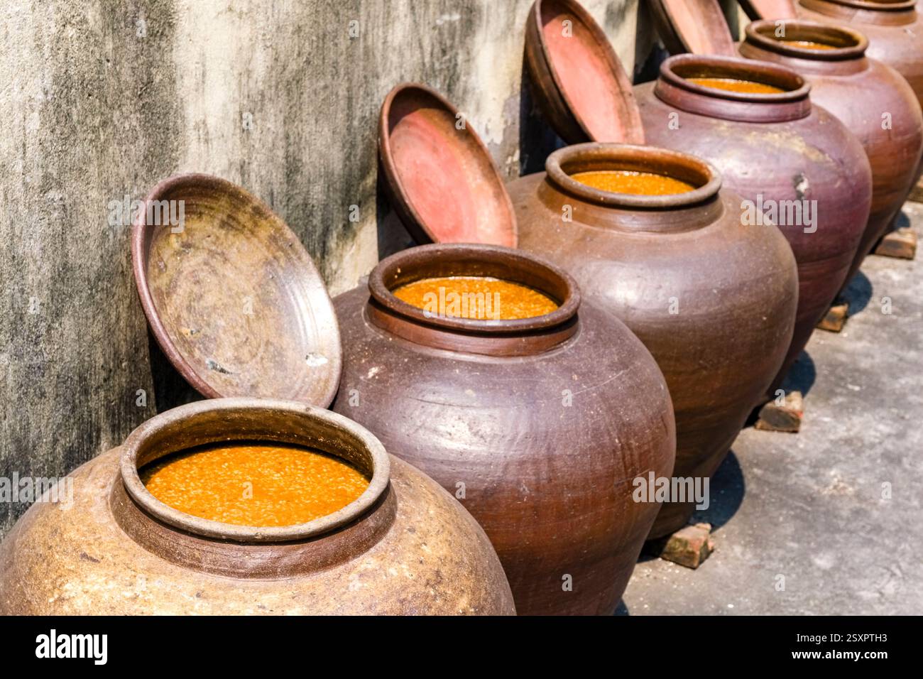 Soy sauce is made in large earthenware pots in a backyard in the small ...