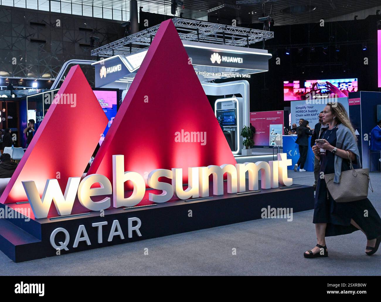 WEB SUMMIT QATAR 2025 - DAY THREE People walk past a Web Summit logo at DECC during the third ...