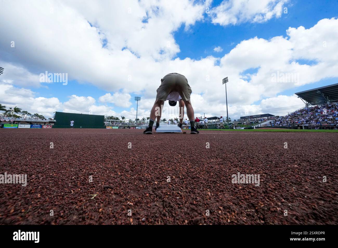 A grounds keeper places the third base before a spring training ...
