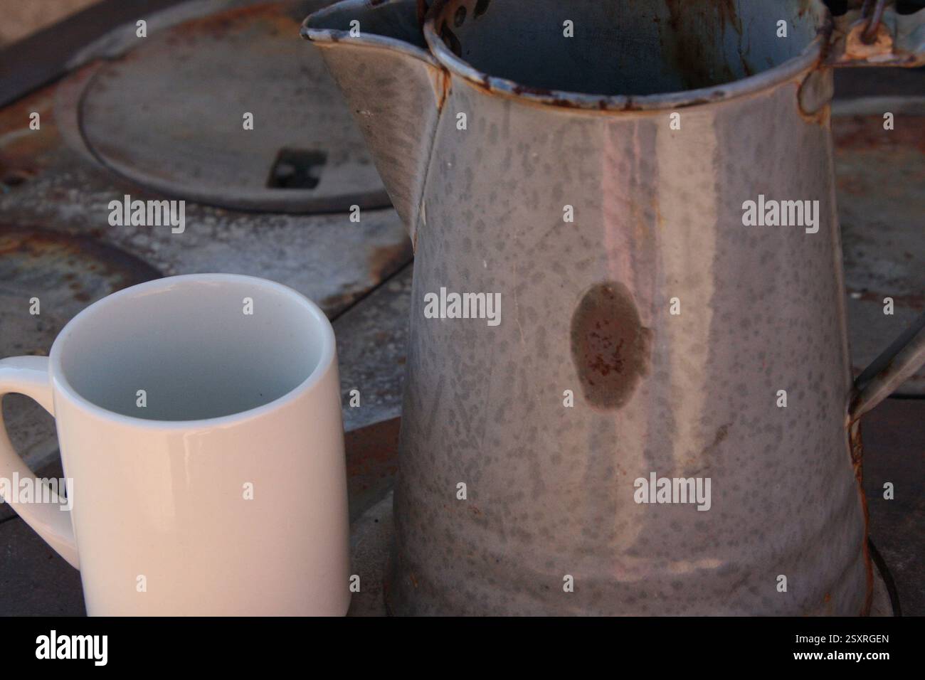 An old metal coffee pot and a ceramic cup sit on an old fashioned ...