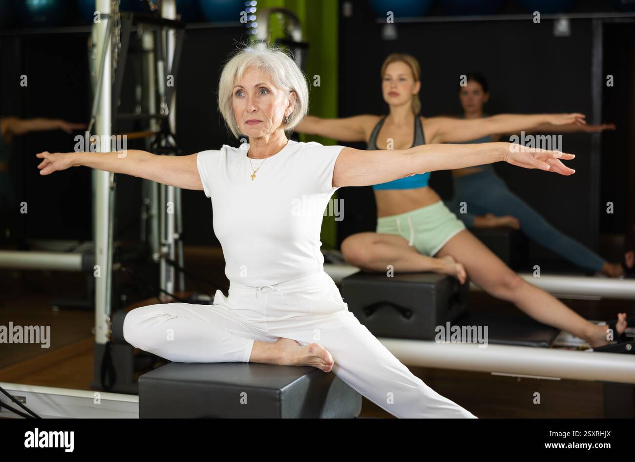 Gray-haired woman sitting on a Pilates platform Stock Photo - Alamy