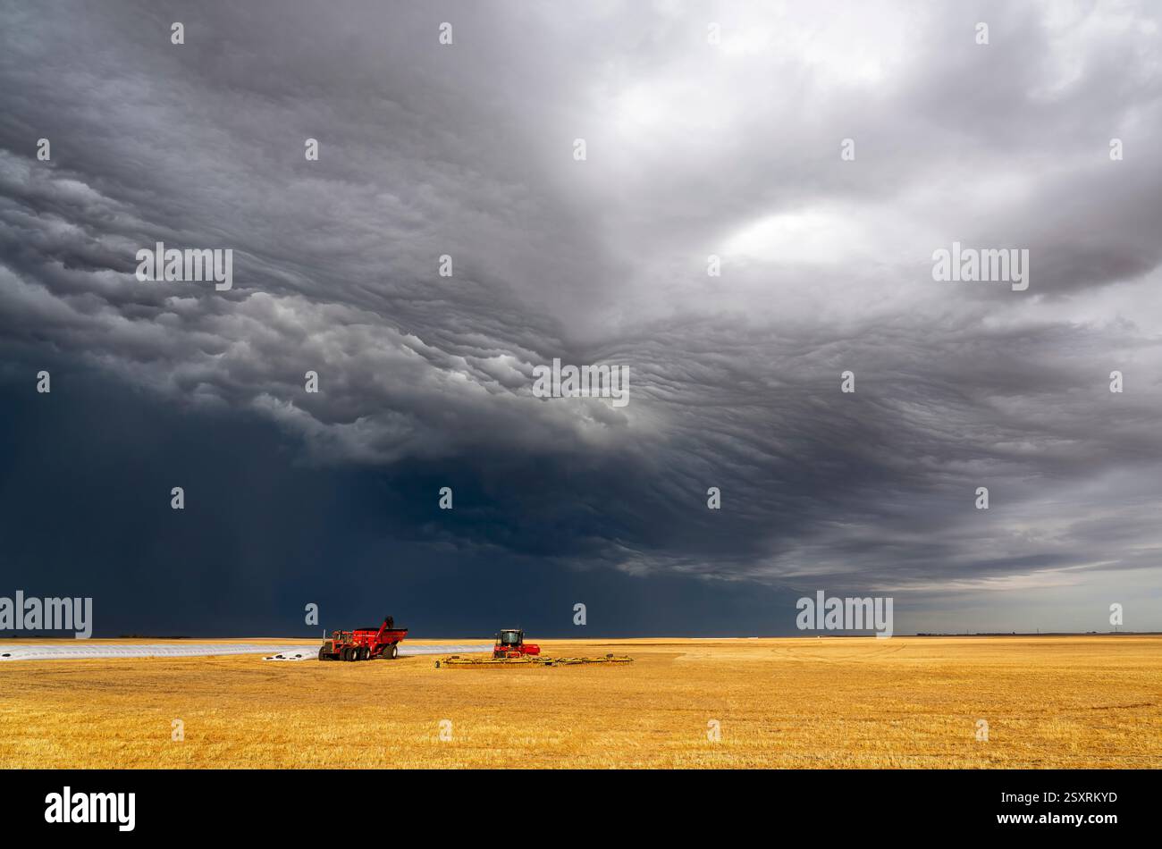 Dramatic shelf cloud forming over farmland with agricultural machinery ...