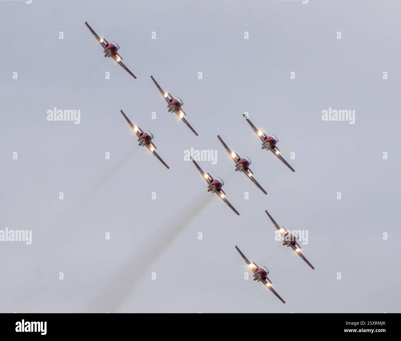 Seven military jets are flying in formation with their landing lights ...
