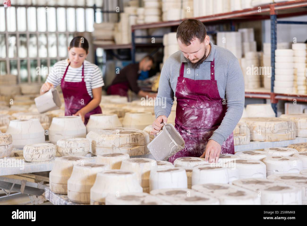 Artisan pouring slip into casting molds in pottery workshop Stock Photo ...