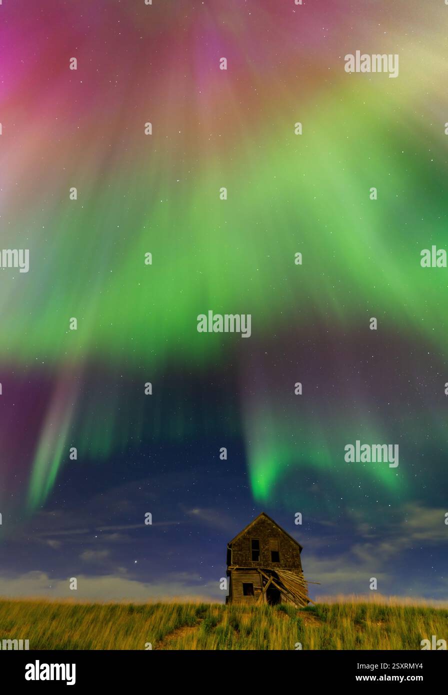 Aurora borealis glowing over an old abandoned house in a field at night ...
