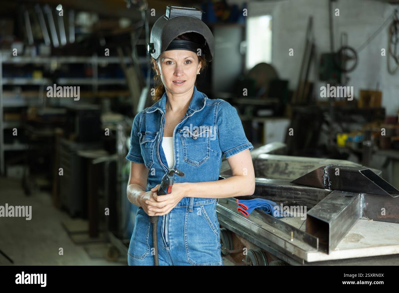 Portrait of a female welder standing with a welding semi-automatic ...