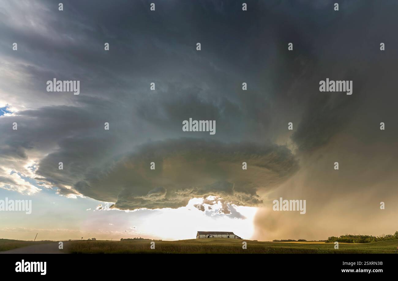 Dramatic supercell storm clouds forming over a farm at sunset, creating ...
