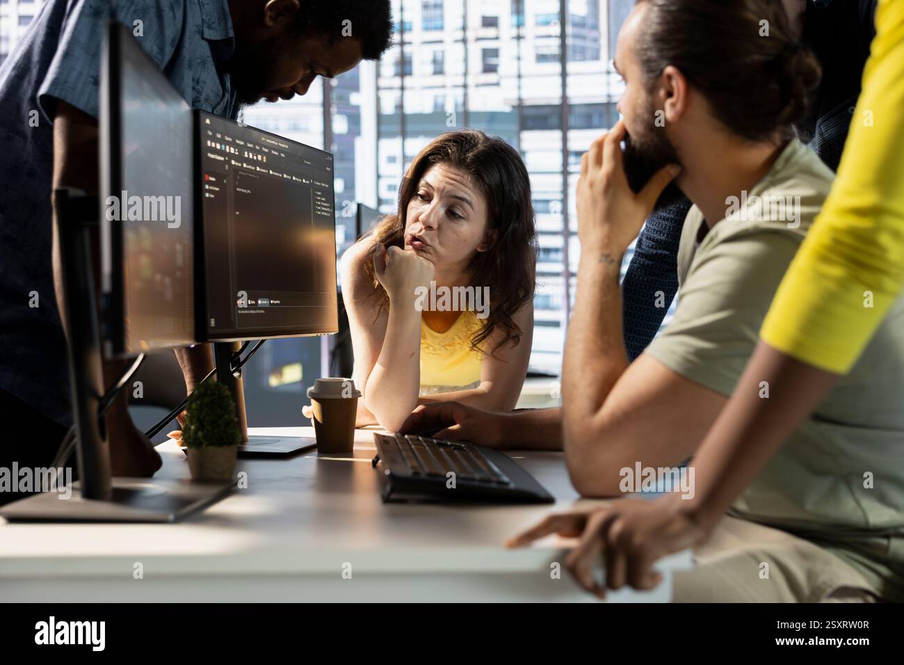 IT staff members gathered together to conduct code review to fix bugs, identifying technical ...