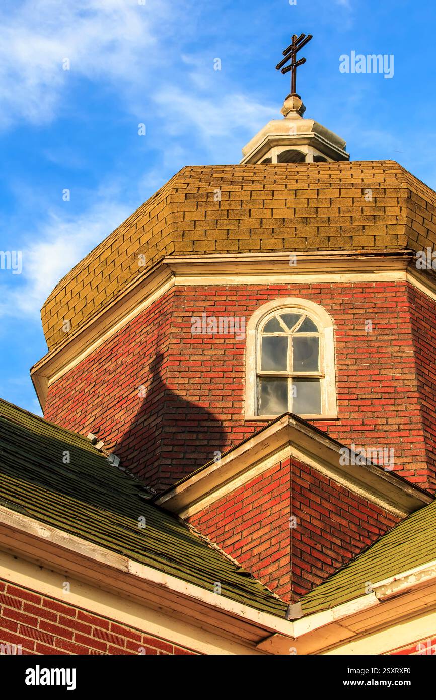 Brick building with a green roof and a cross on top. The building has a ...