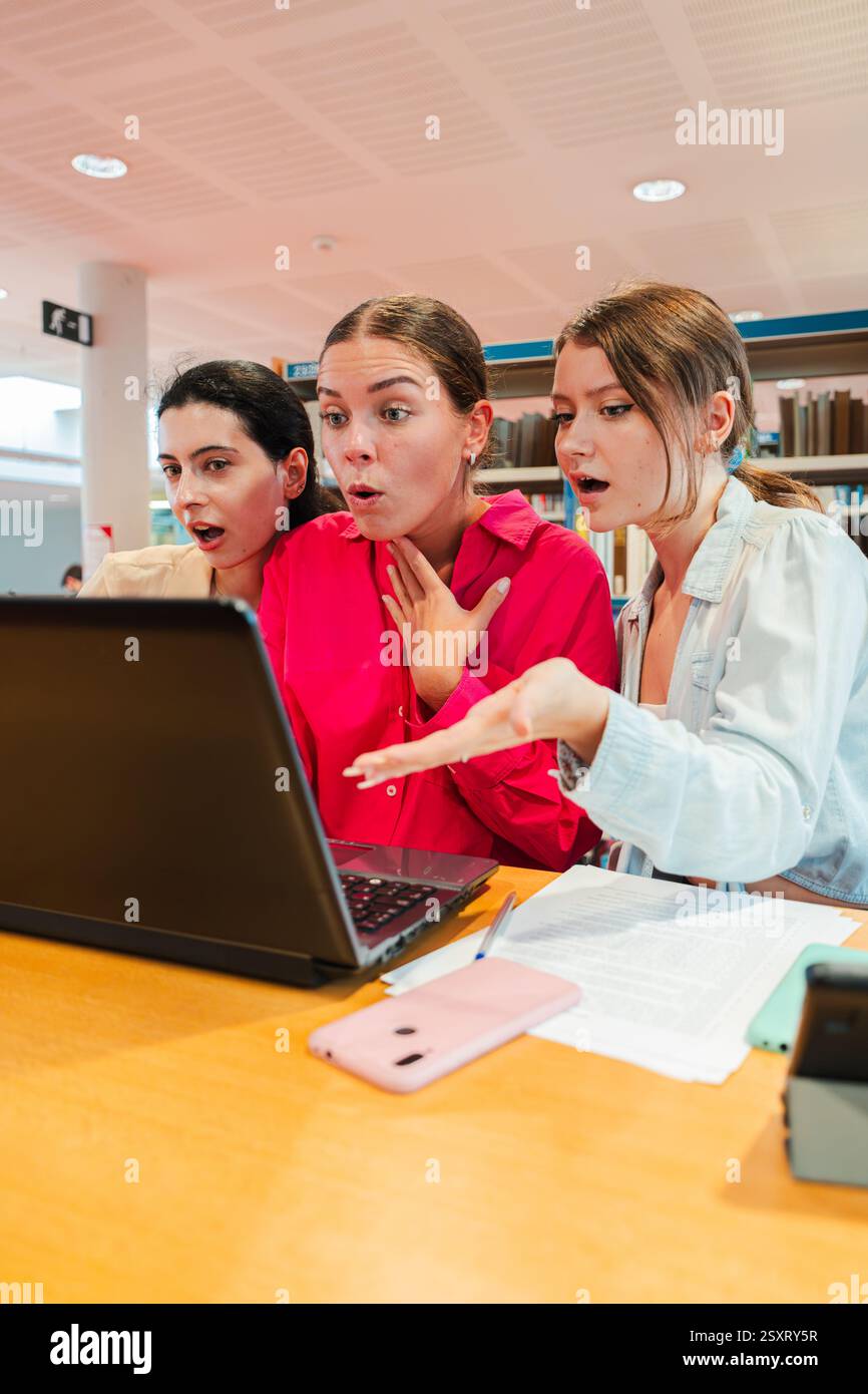 Three surprised girls engaged in an exciting moment while using a ...