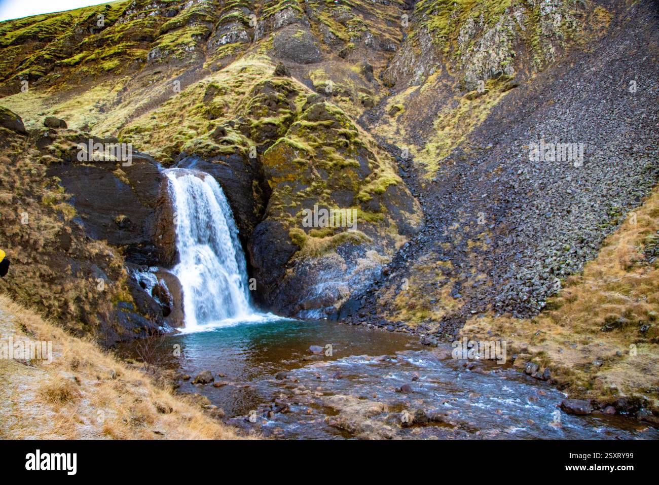 Waterfall cascading down a rugged, moss-covered mountainside ...