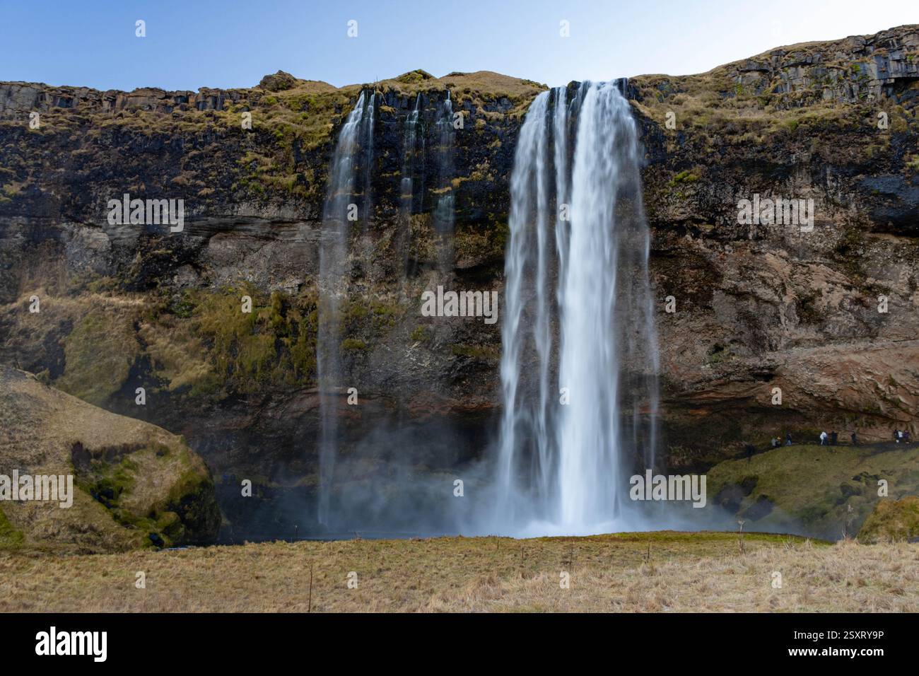 A majestic waterfall cascades down a steep cliff, surrounded by rugged ...