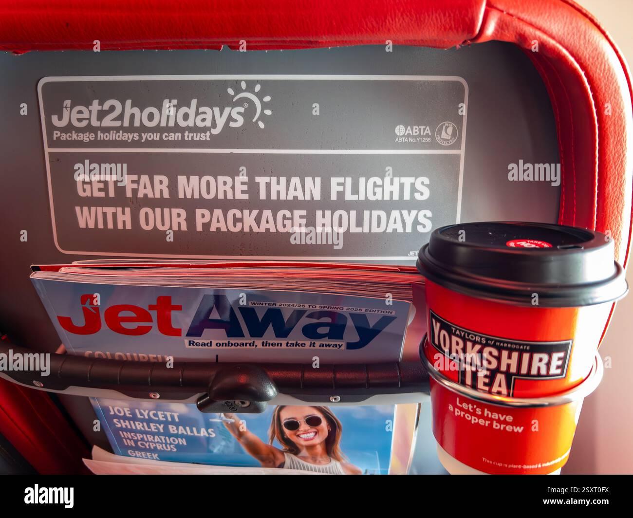 Airplane seat with Jet2holidays advertisement and a cup of Yorkshire ...