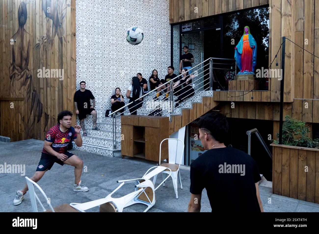 Workers at a bar play with a soccer ball outside their workspace during ...