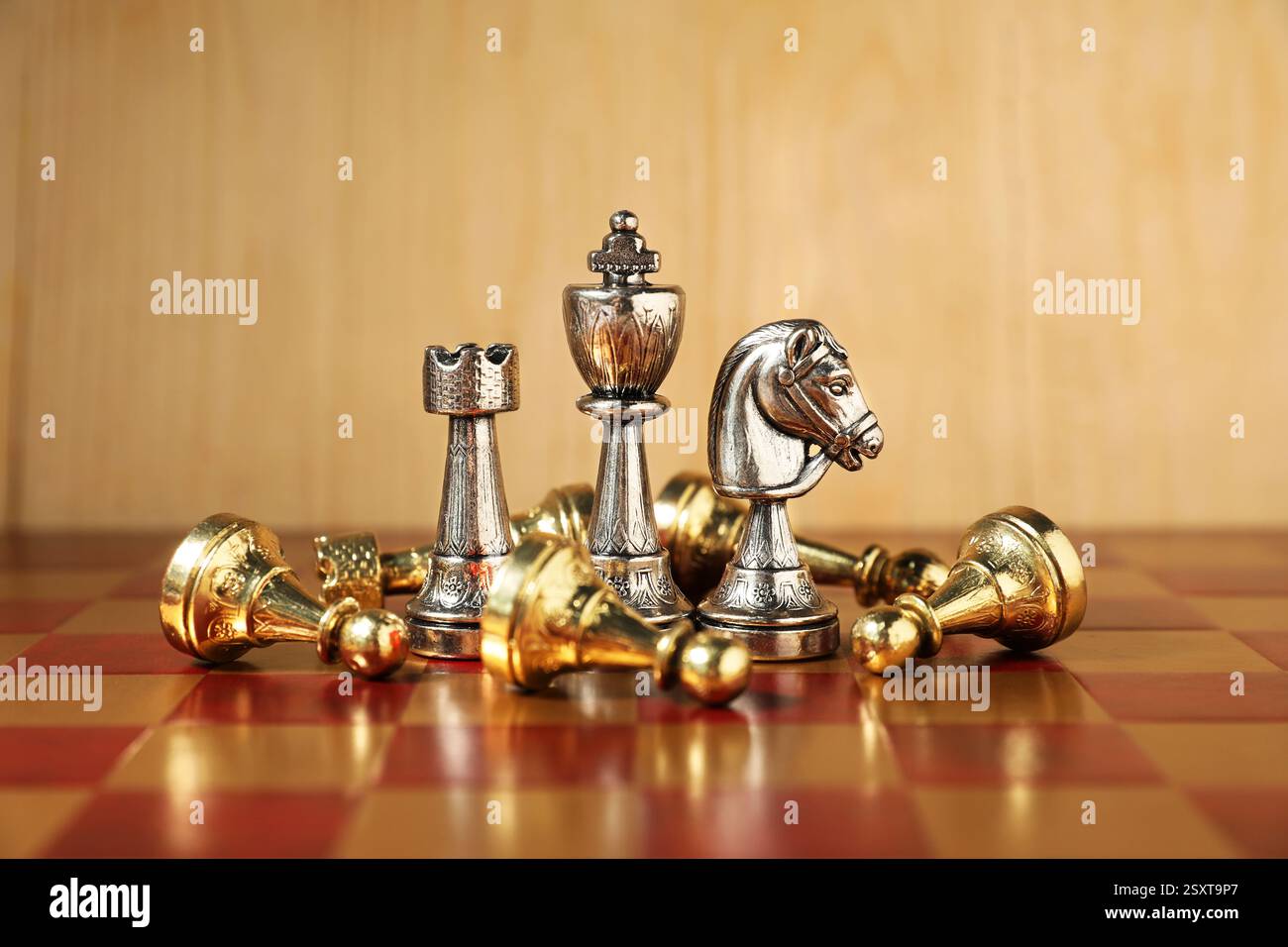 Silver chess pieces among fallen golden ones on chessboard. Competition ...