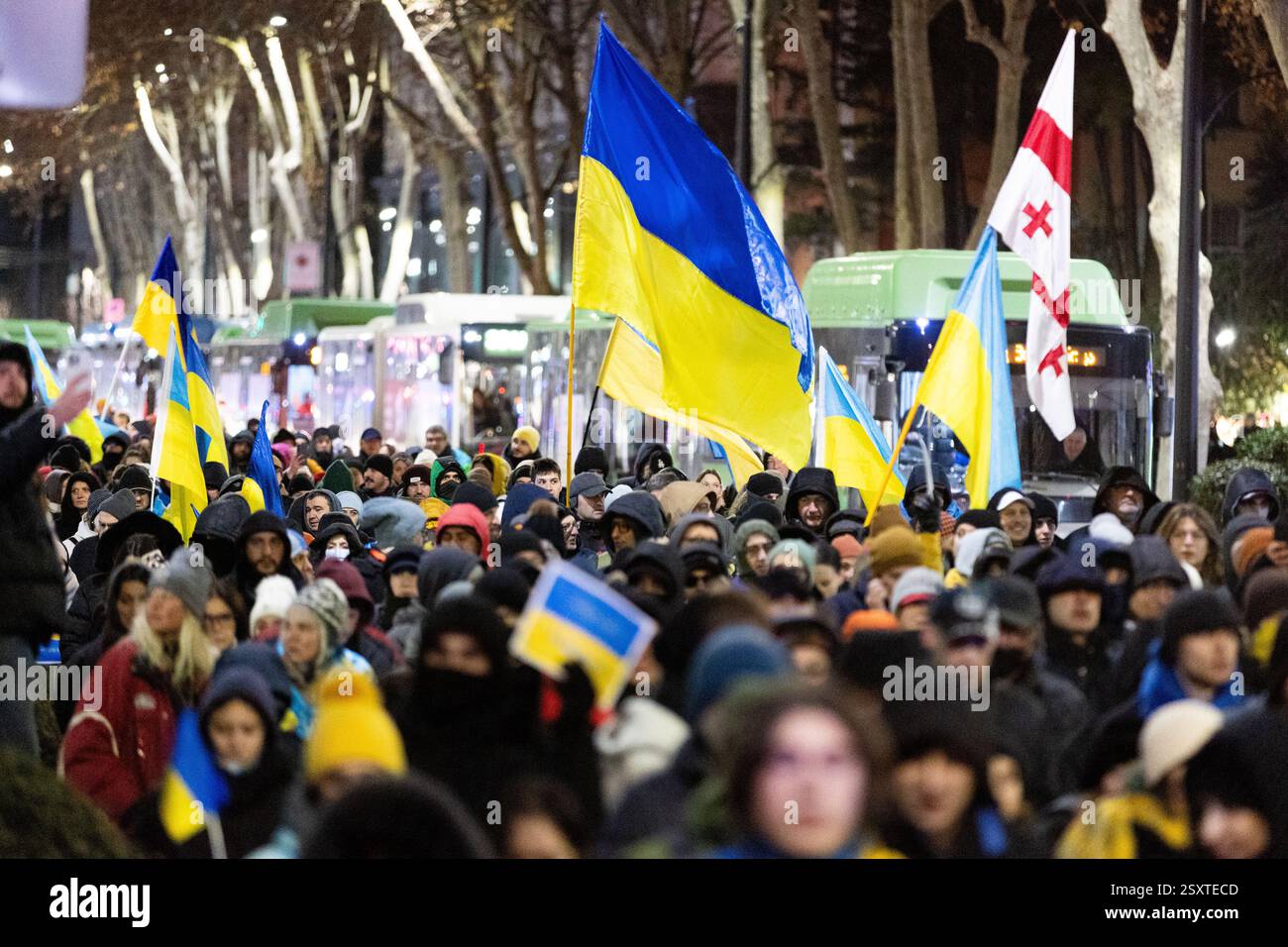 A large gathering of protesters floods the street, holding Ukrainian ...