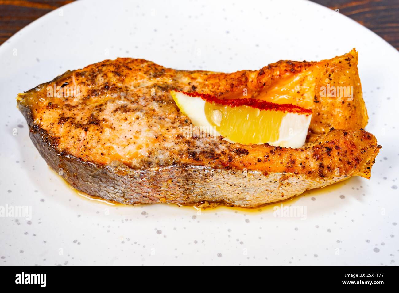 A beautifully grilled salmon fillet rests on a white plate, accented ...