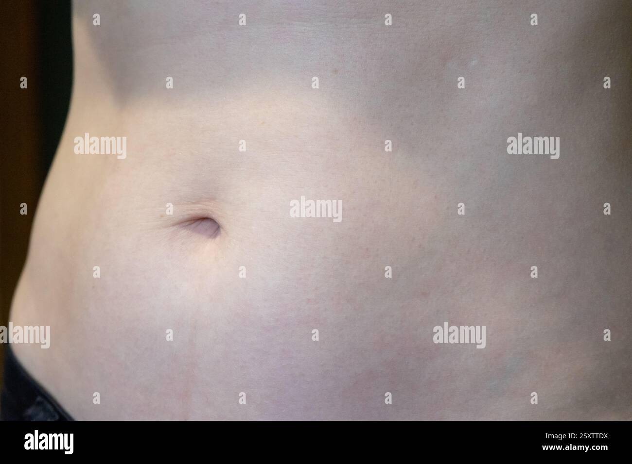 The image depicts the skin of a midsection, showcasing a flat abdomen ...
