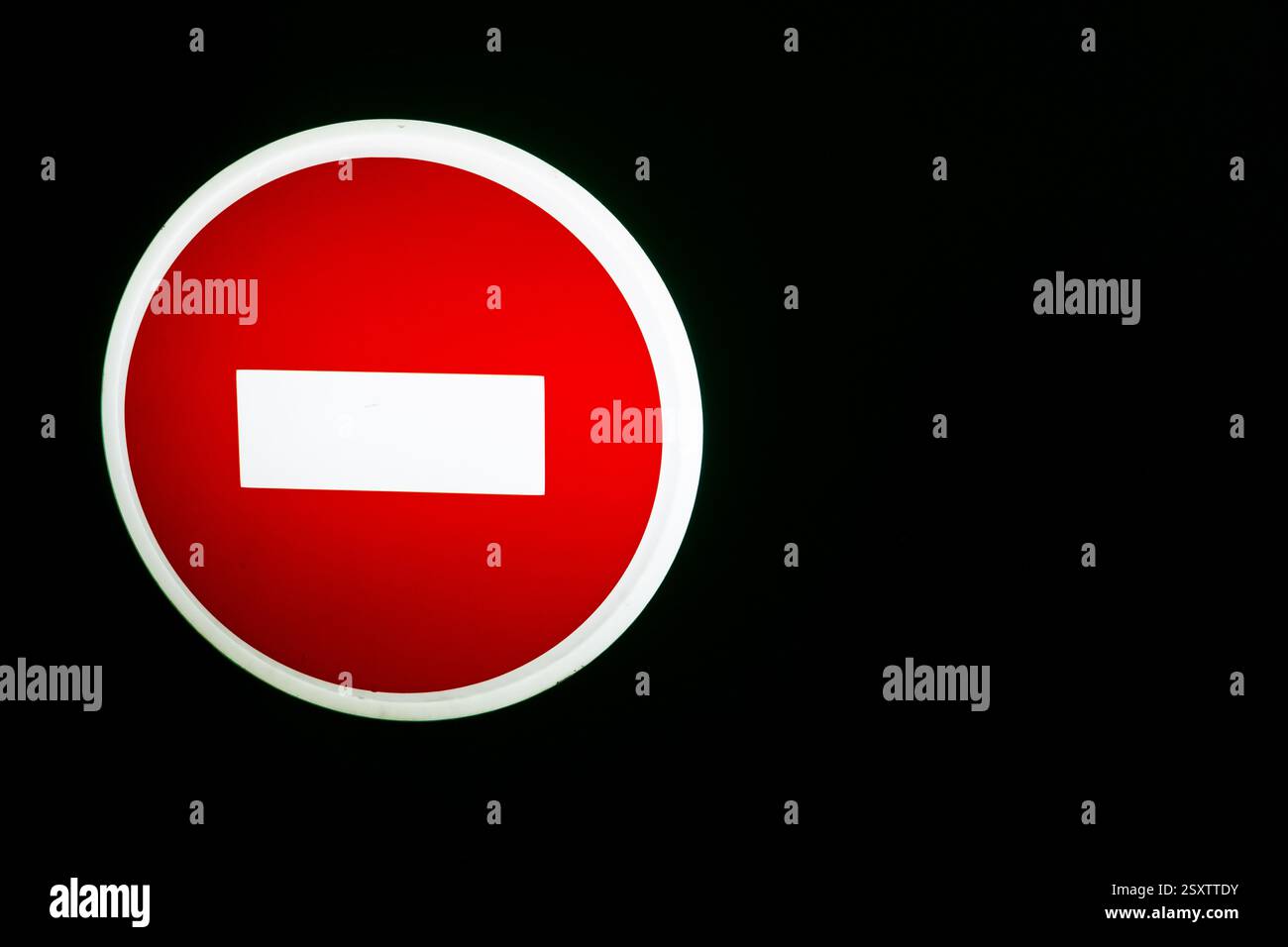 A bright red no entry sign against a black background clearly indicates ...
