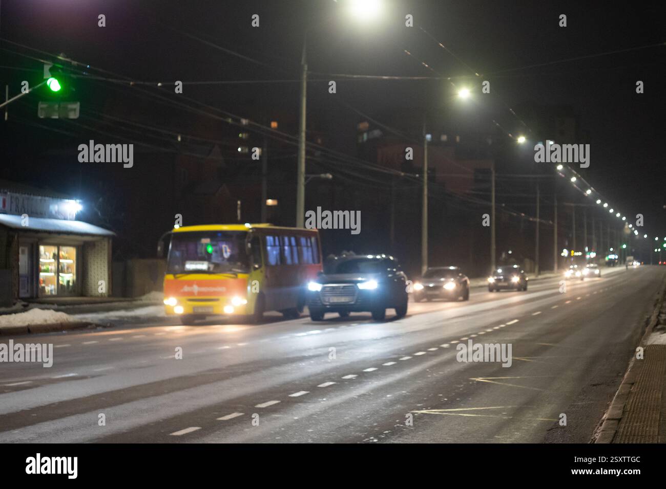 Vehicles navigate a city street illuminated by bright streetlights and ...