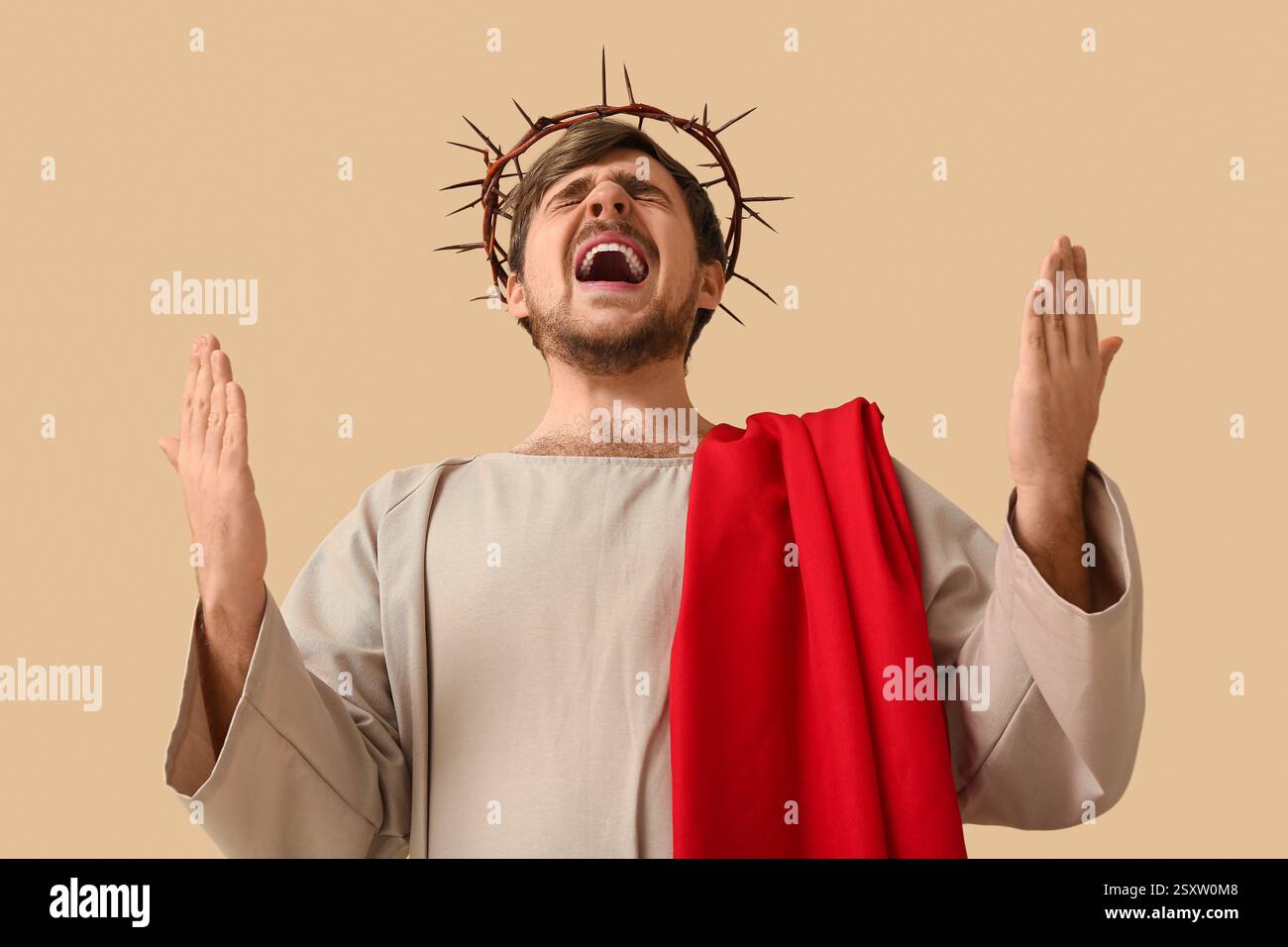 Man in Jesus robe and crown of thorns with outstretched hands screaming ...