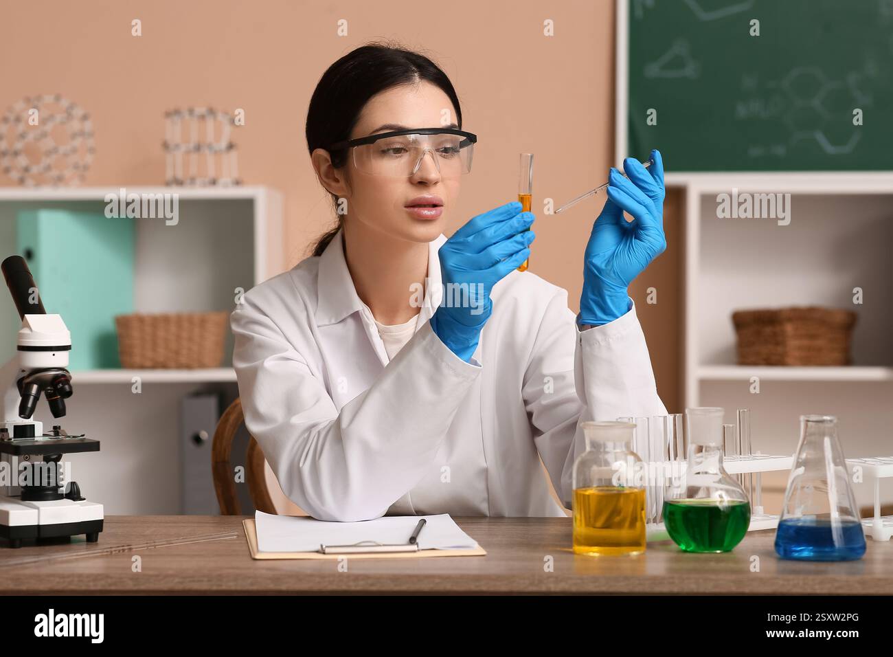 Female inventor with test tube at table in laboratory Stock Photo - Alamy