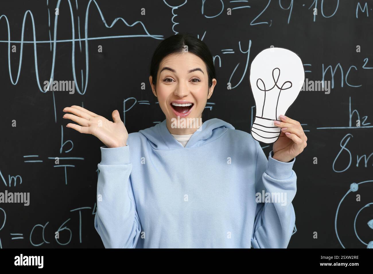 Happy female inventor with paper light bulb near scientific formulas on ...