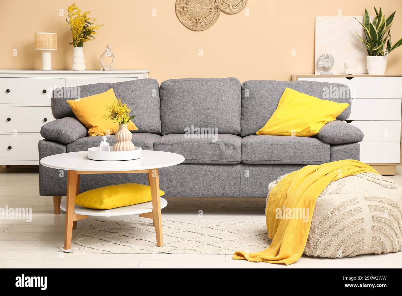 Interior of living room with sofa, pouf and mimosa flowers in vases ...
