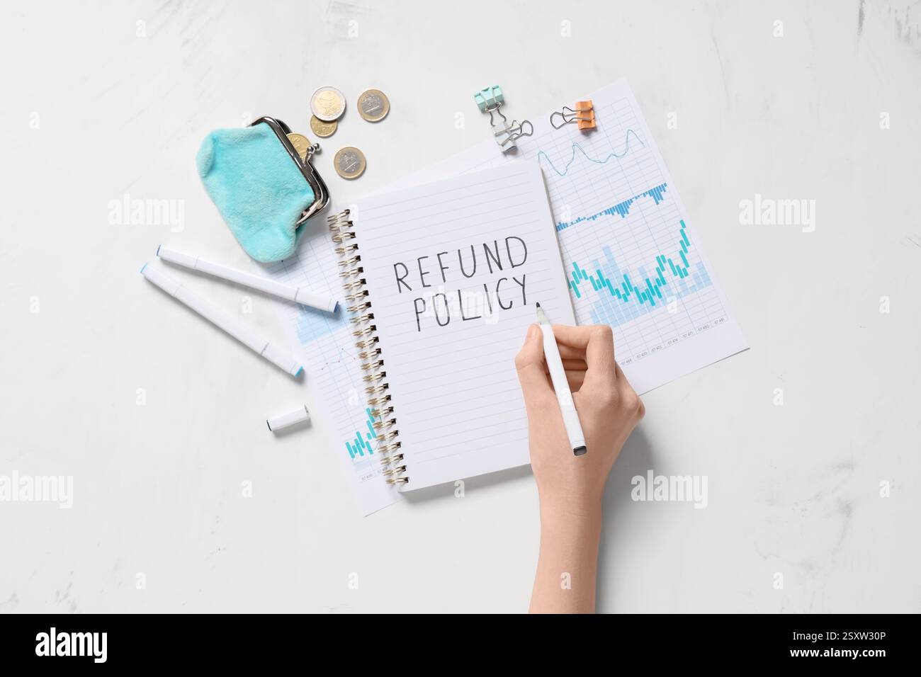 Female hand with graphics, coins, notebook and text REFUND POLICY on ...