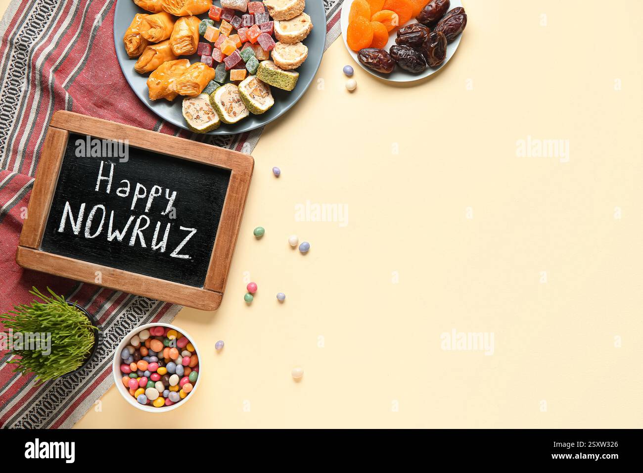 Chalkboard with text HAPPY NOWRUZ, traditional sweets and green wheat ...