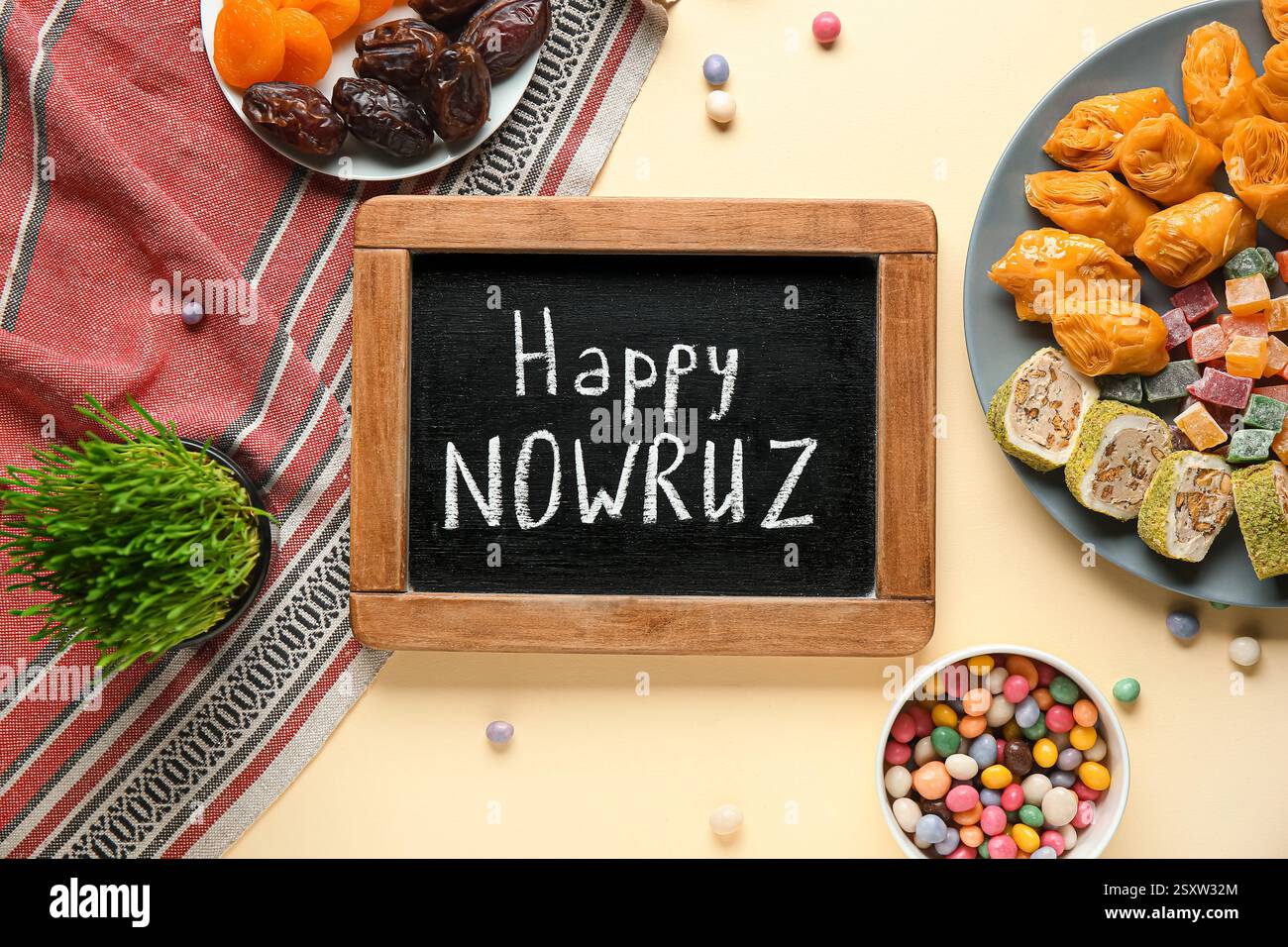 Chalkboard with text HAPPY NOWRUZ, traditional sweets and green wheat ...