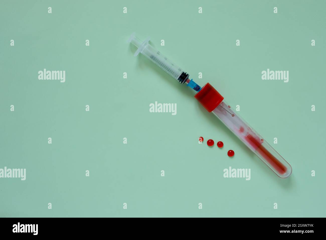 Syringe, and test tube with red plug and red blood. Blood drops on the ...