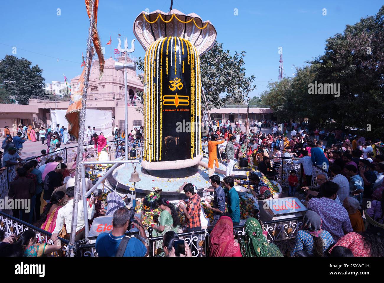 Hindu devotees offer prayer around a Shivling, a representation of ...