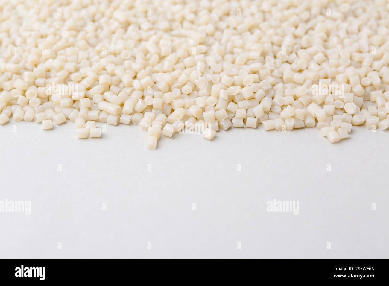 Pile of plastic granules on white background, closeup. Space for text ...