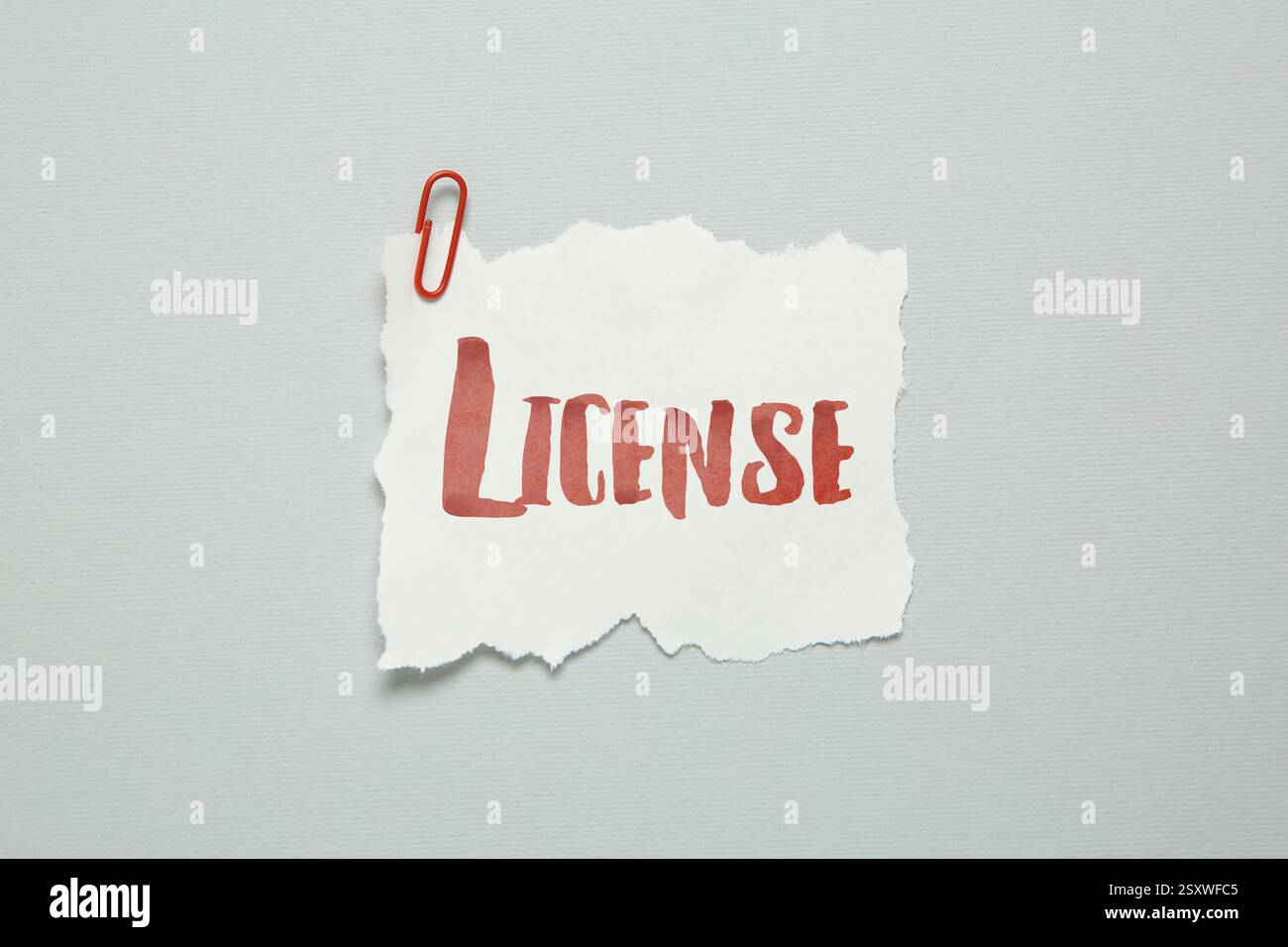 Piece of paper with word License and paperclip on white background, top ...