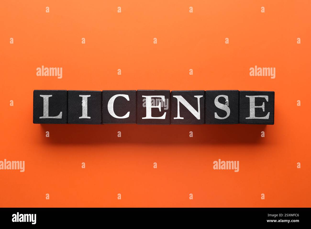 License word made of black cubes with letters on dark orange background ...
