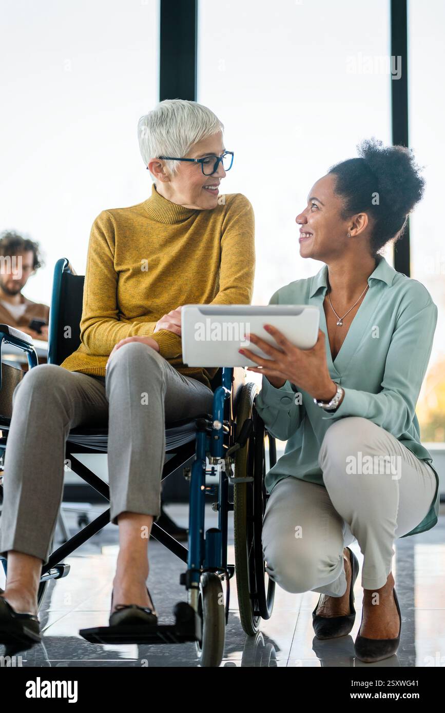 Disabled woman in wheelchair looking at computer, discussing startup ...