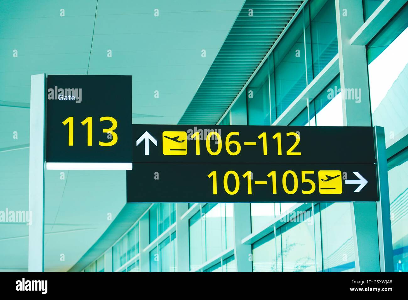 Brightly lit airport signage displays gate numbers 106 to 112, 101-105, 113. Directional arrows ...