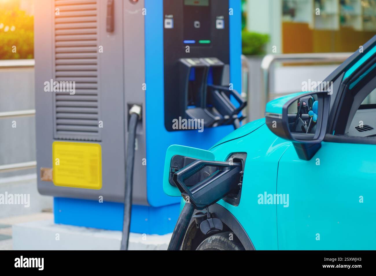 A compact electric vehicle is plugged into a charging station in a ...