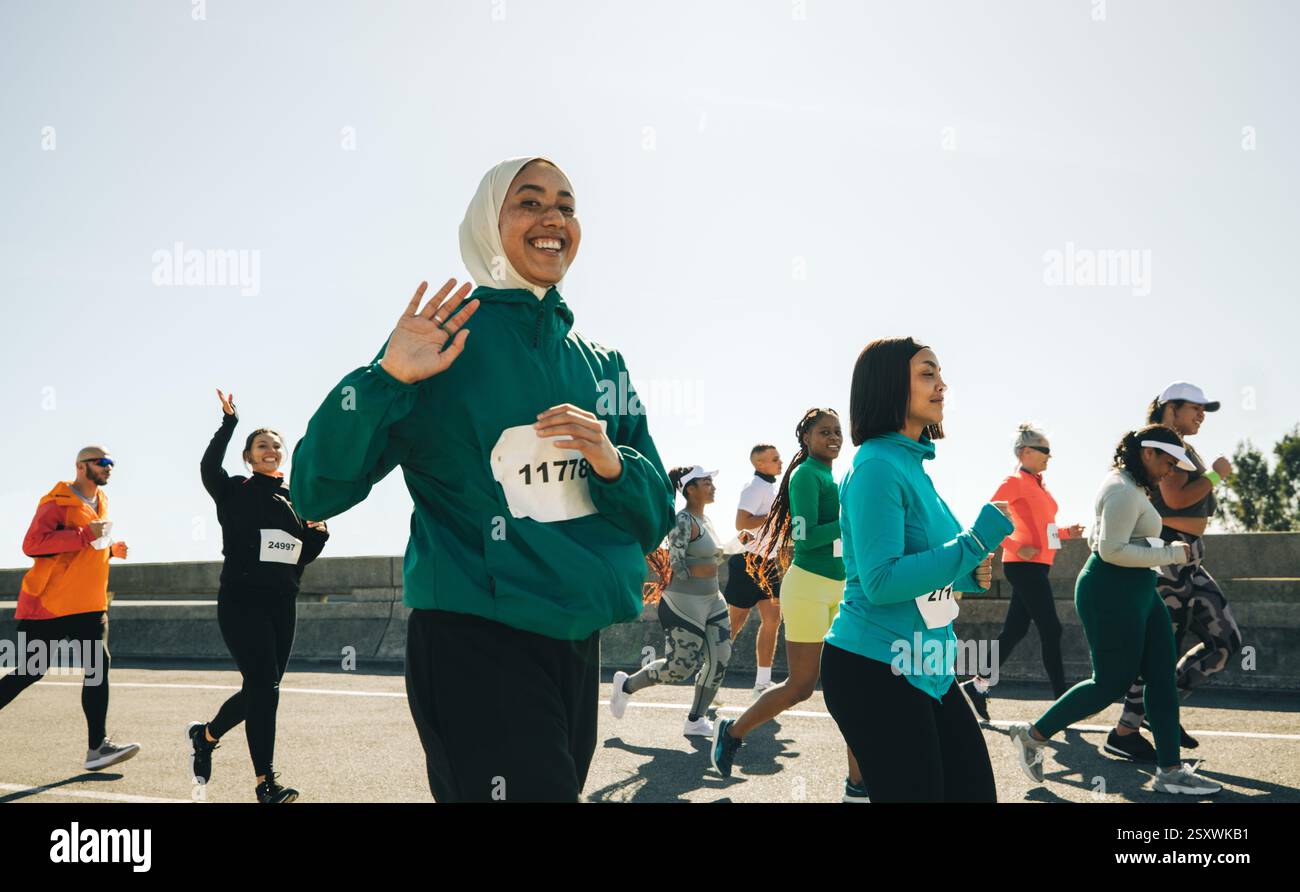 A joyful Muslim female runner waves to the camera while participating ...